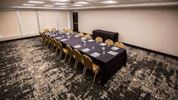 Uma sala de conferência com uma mesa comprida, cadeiras e uma tela de projetor.
