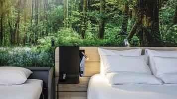 Quarto com cama, mesas de cabeceira e vista para uma floresta.
