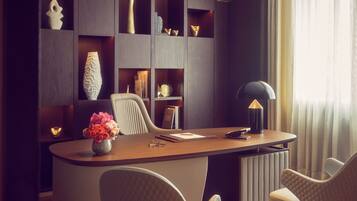 Um espaço de escritório moderno com uma mesa de madeira, duas cadeiras, um vaso de flores e prateleiras com objetos decorativos.