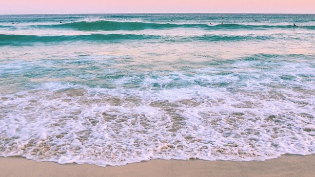 Uma praia com ondas e céu claro.