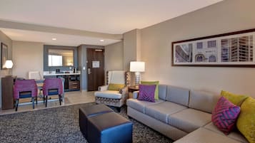 Quarto de hotel moderno com área de estar, espaço para refeições e cozinha compacta.