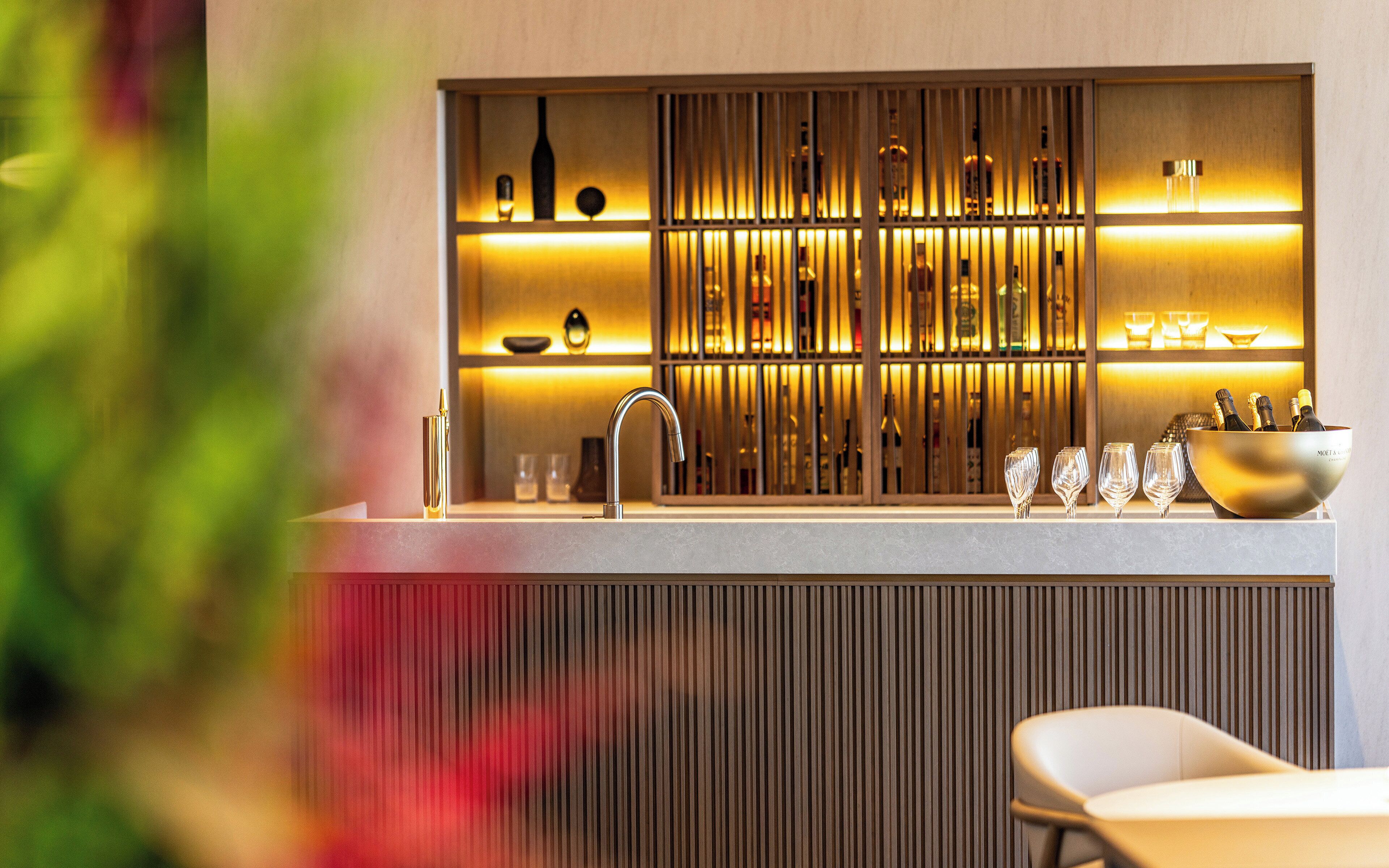 Uma área de bar moderna com adega embutida, pia e espaço para sentar.