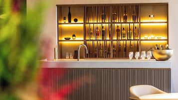 Uma área de bar moderna com adega embutida, pia e espaço para sentar.