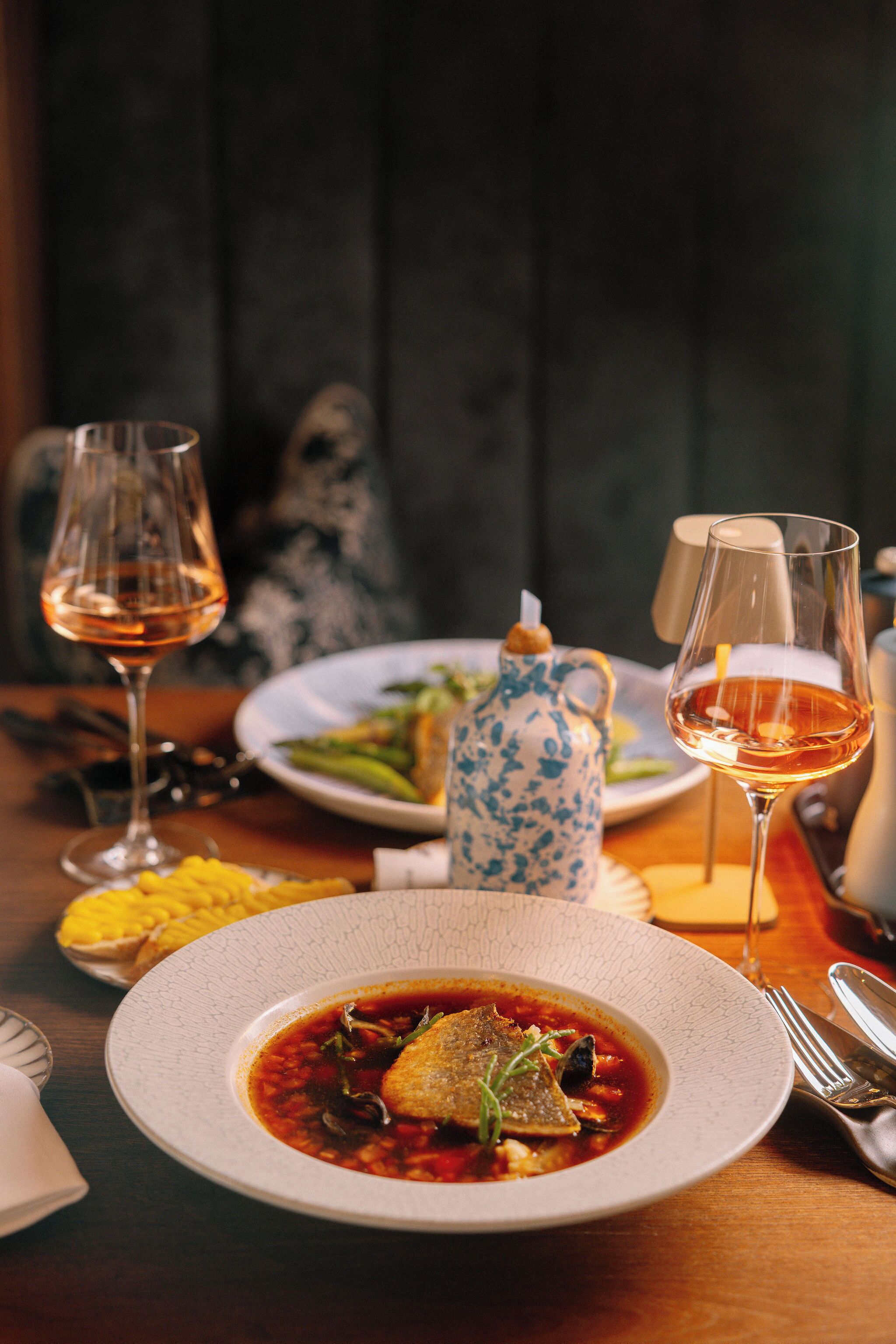 Mesa de jantar com uma tigela de sopa, dois copos de vinho e um bule de chá.