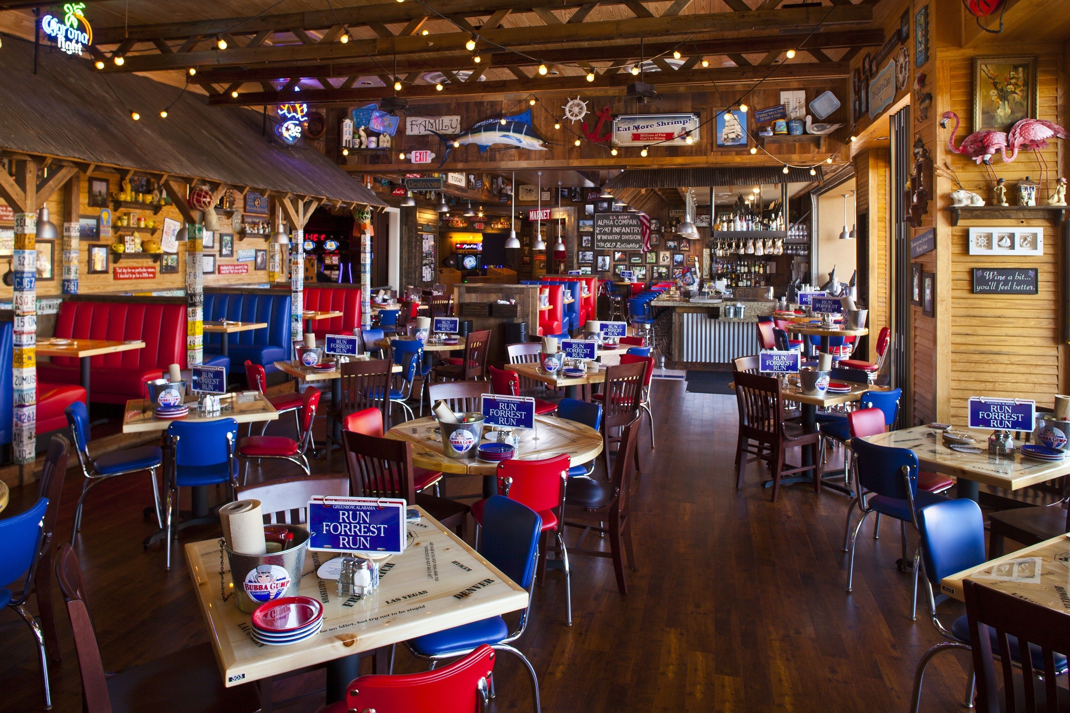 Um restaurante com cabines e mesas, teto de madeira, diversos sinais e decorações.