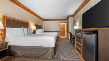 Quarto de hotel com duas camas, televisão, frigorífico e secretária com candeeiro.