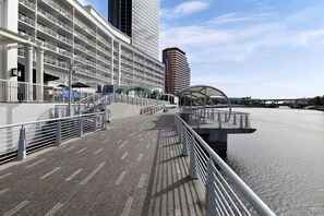 Hotel à beira-mar com design moderno, apresentando um amplo calçadão, área coberta e vista para a água.