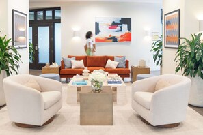 Uma sala de estar moderna com sofá, duas poltronas, uma mesa de centro e um quadro na parede.