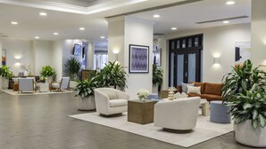 Um hall amplo com design moderno, com diferentes áreas de estar e um balcão de recepção.