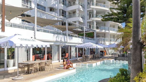 Um hotel com piscina, área de estar externa e várias varandas.
