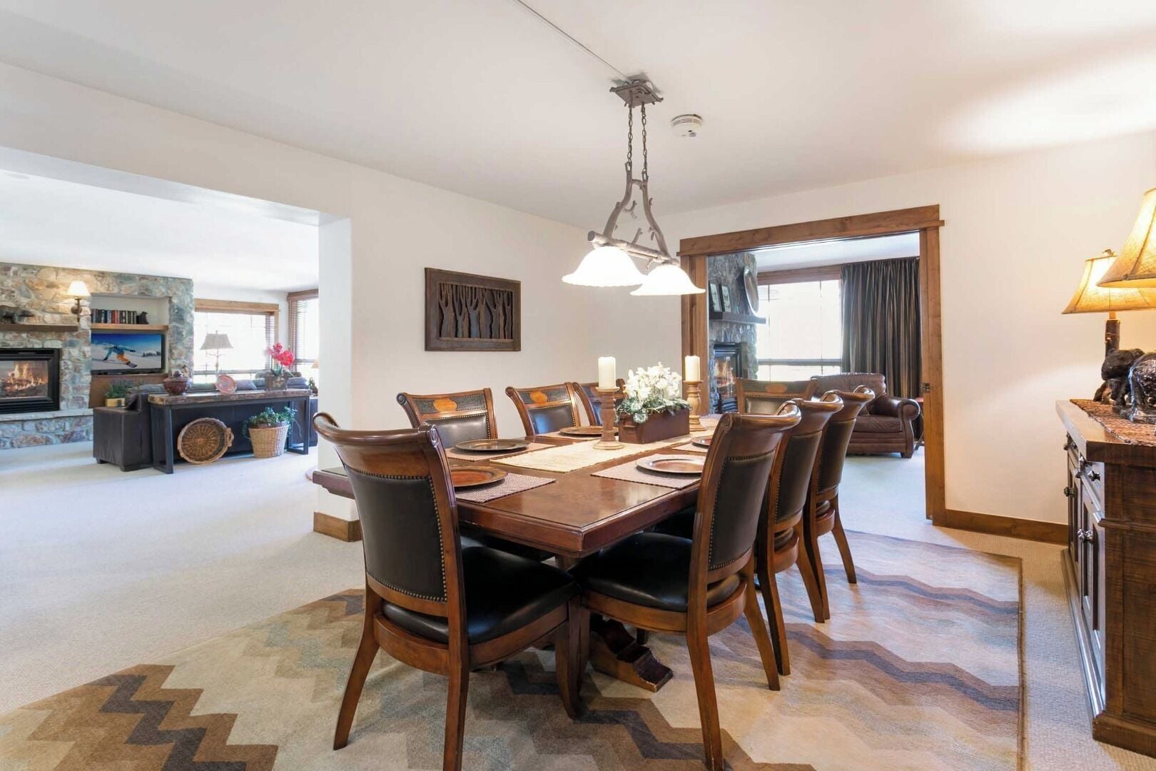 Uma ampla área de refeições com uma grande mesa de madeira, várias cadeiras e um lustre.
