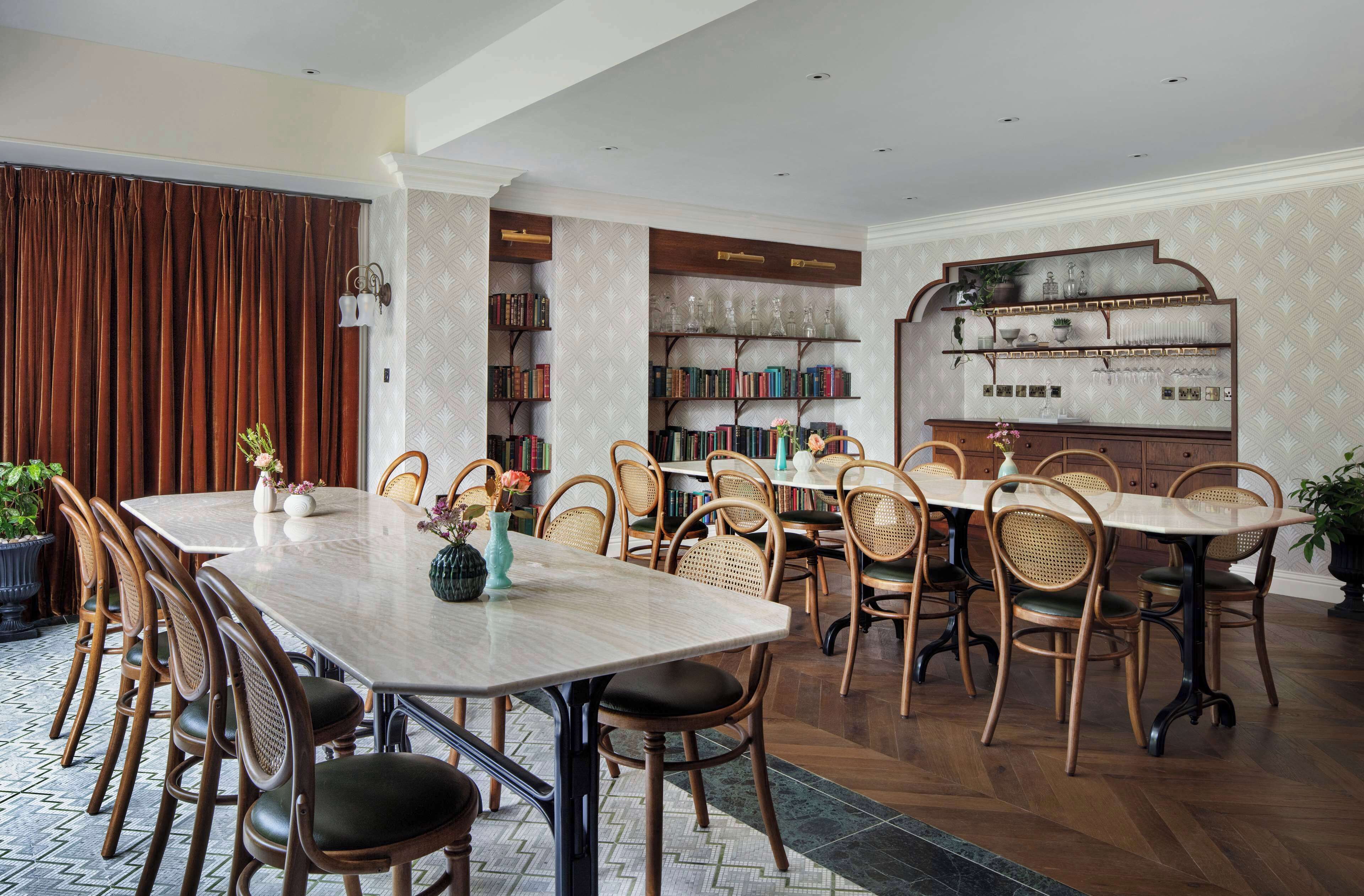 Uma sala de jantar com uma mesa grande e cadeiras, rodeada por estantes de livros e um aparador decorativo.