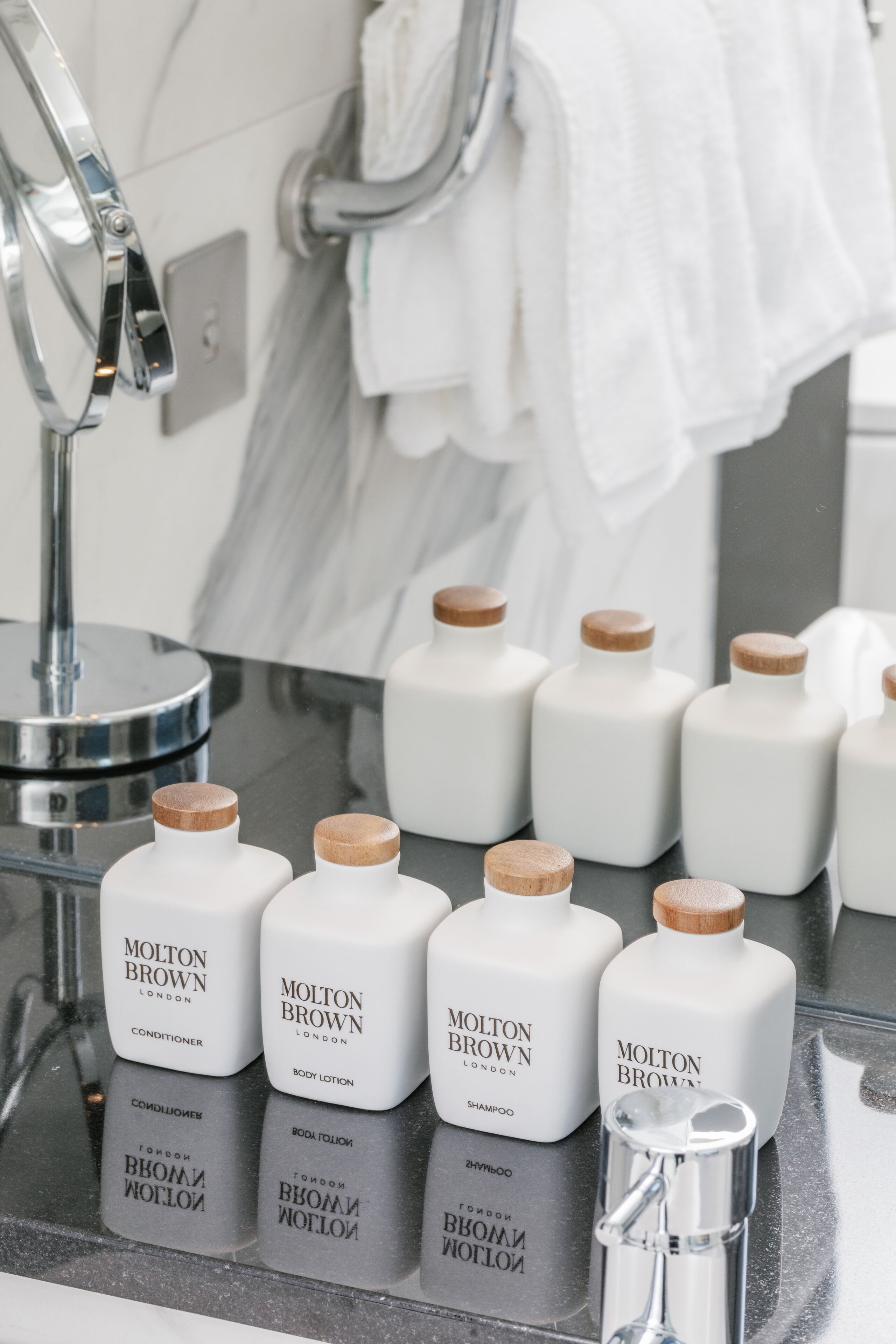 Uma bancada de banheiro com vários produtos Molton Brown London, incluindo condicionador, loção corporal e shampoo.