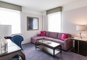 Uma sala de estar moderna com um sofá, uma mesa de centro, um abajur e um quadro na parede.