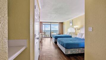 Quarto de hotel com duas camas, varanda, uma pequena mesa com cadeiras e vista do céu.