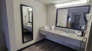 Uma casa de banho de hotel com um espelho grande, uma pia e um secador de cabelo.