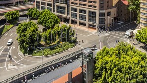 Um edifício de vários andares com uma placa chamativa 'PARKROYAL', rodeado por outros edifícios altos e um céu azul límpido.
