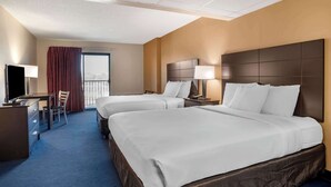 Quarto de hotel com duas camas, uma escrivaninha, uma cadeira, uma televisão e uma janela com cortinas.