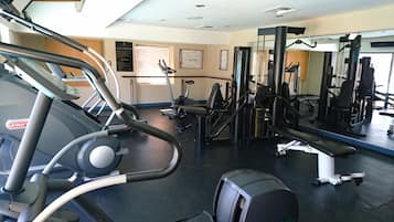 Ginásio com aparelhos de cardio, equipamentos de musculação e um espelho.