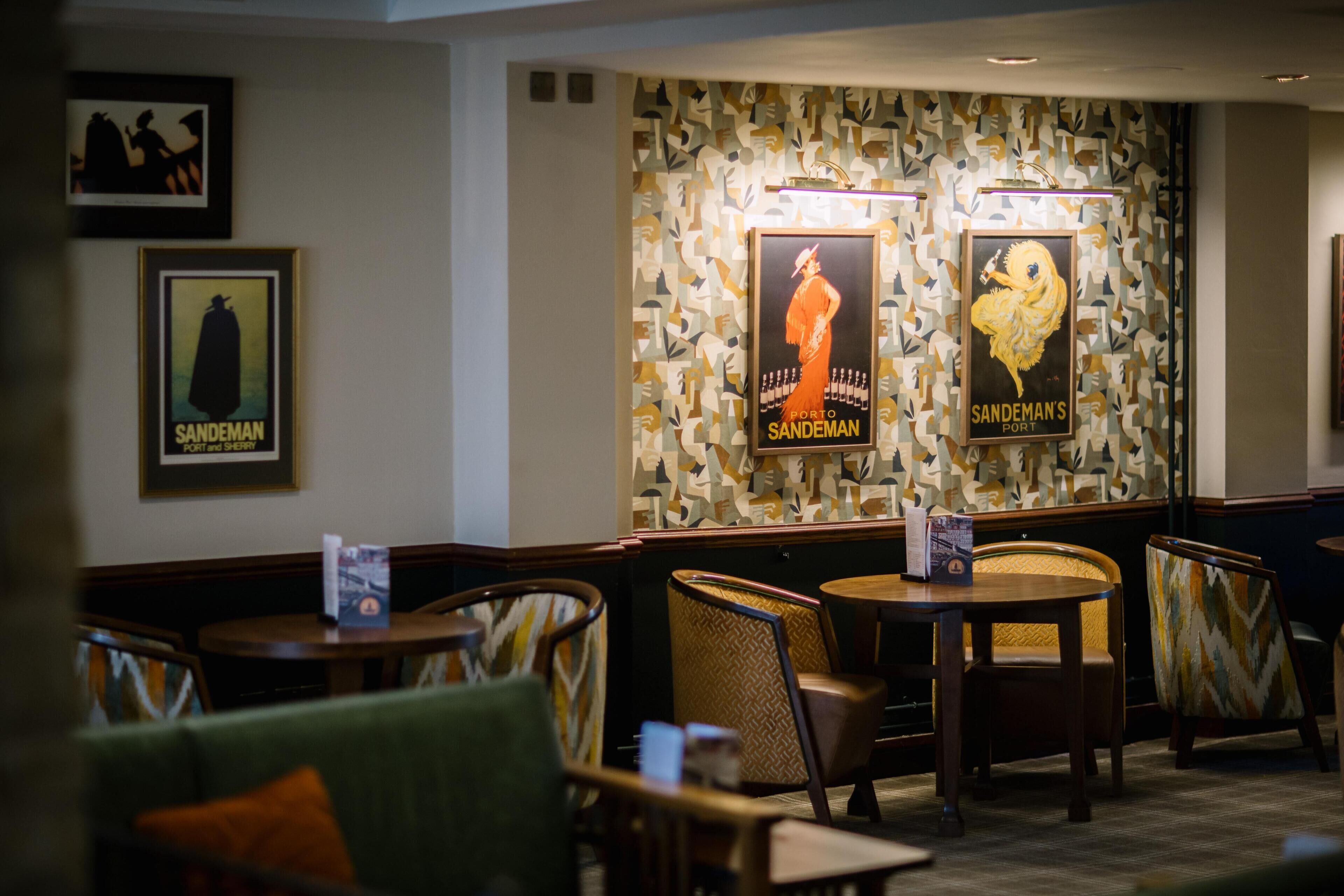 Interior de restaurante com mesas, cadeiras e cartazes na parede.