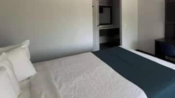Quarto de hotel com uma cama grande, uma escrivaninha e um guarda-roupa.