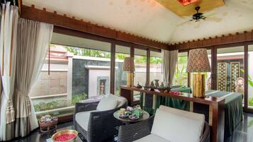 Quarto com móveis de vime, ventoinha no teto e vista para o verde lá fora.