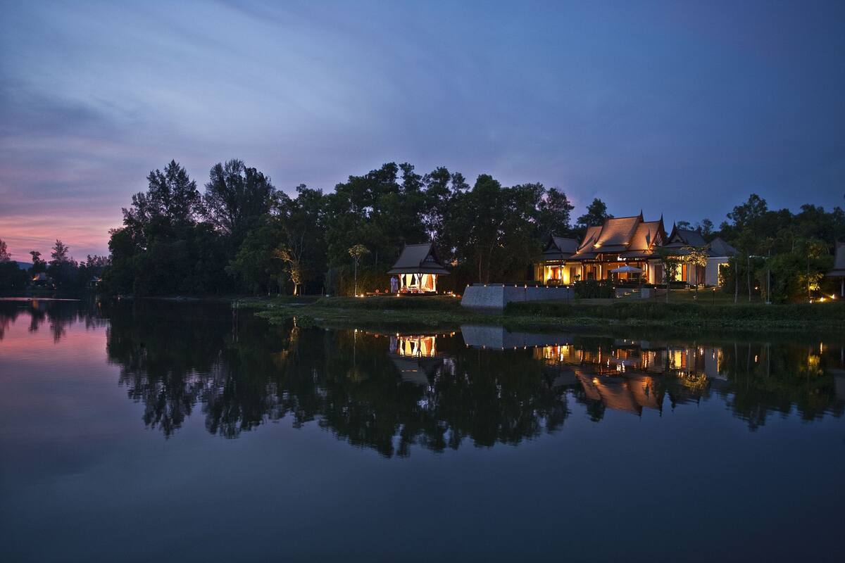 Um imóvel à beira do lago com vários edifícios, incluindo uma casa principal e estruturas menores, refletindo na água.