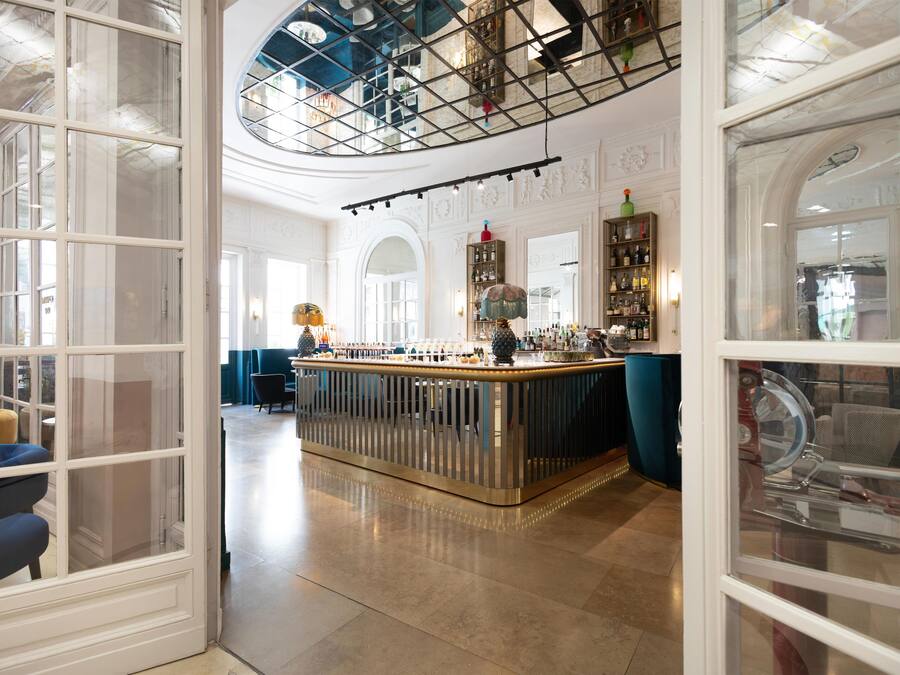 Um espaço amplo de bar com teto alto e balcão central, rodeado por assentos e detalhes decorativos.
