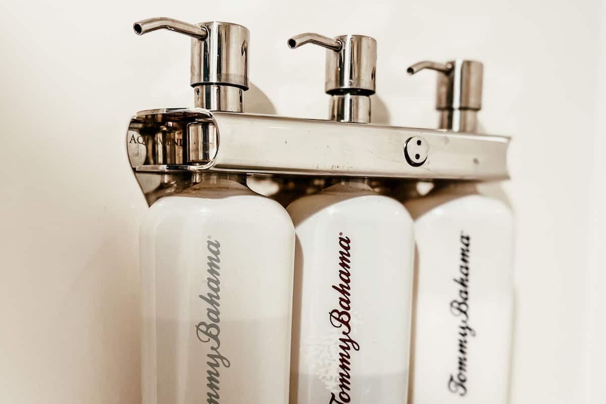 Banheiro com três produtos de higiene pessoal Tommy Bahama: shampoo, gel de banho e condicionador.