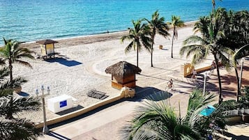 Um resort à beira-mar com área de piscina, palmeiras e posto de salva-vidas.