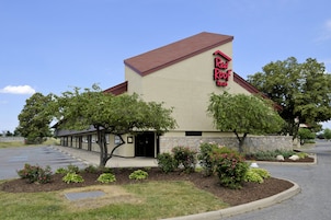 Um Red Roof Inn com fachada de pedra, telhado vermelho e estacionamento.