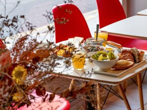 Uma mesa de café da manhã com diversos alimentos, um copo de suco de laranja e um pote de geleia.