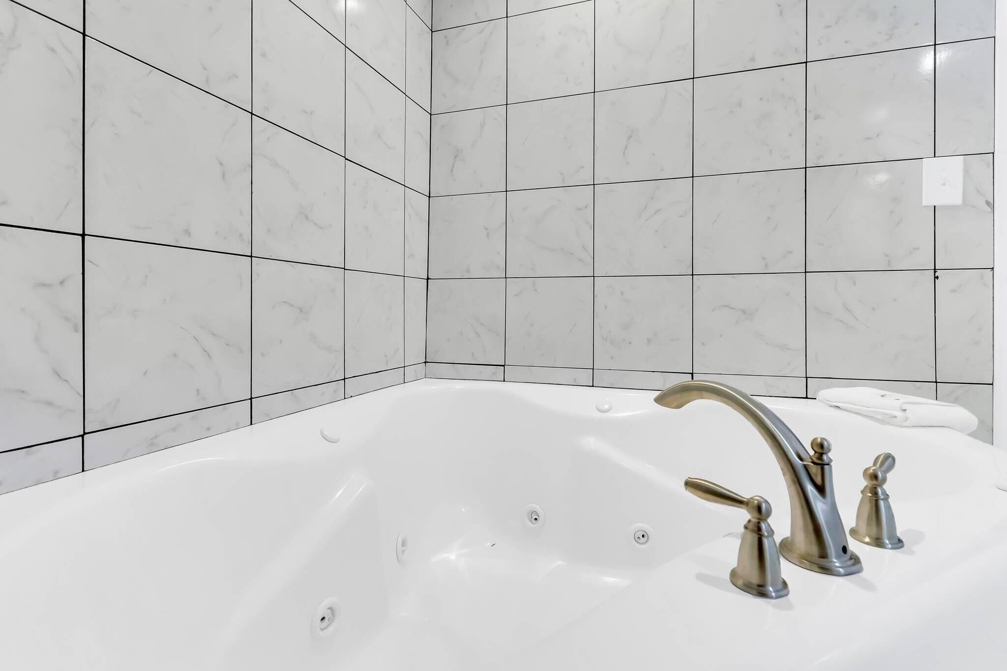 Um banheiro moderno com banheira de apoio, torneiras cromadas e azulejos de mármore branco.