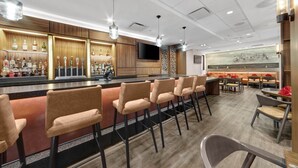 Uma área de bar com um balcão comprido, vários banquetes e uma televisão na parede.