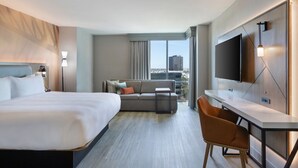 Quarto de hotel com cama grande, sofá, escrivaninha e televisão.