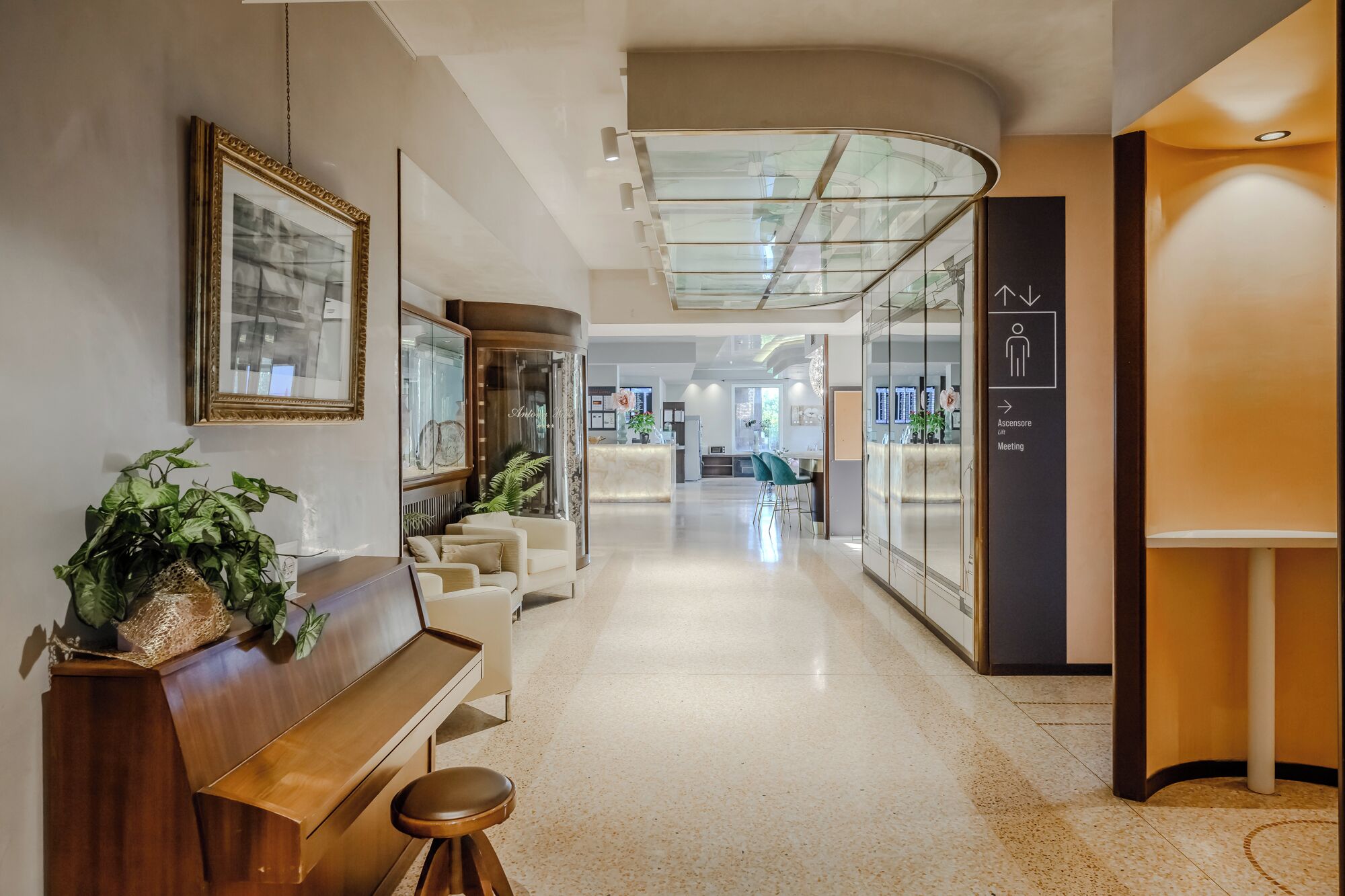 Um hall de hotel moderno com balcão de recepção, área de estar e salas de reunião com paredes de vidro.