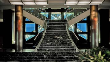 Uma escadaria imponente com estrutura de vidro, que dá acesso a um andar superior.