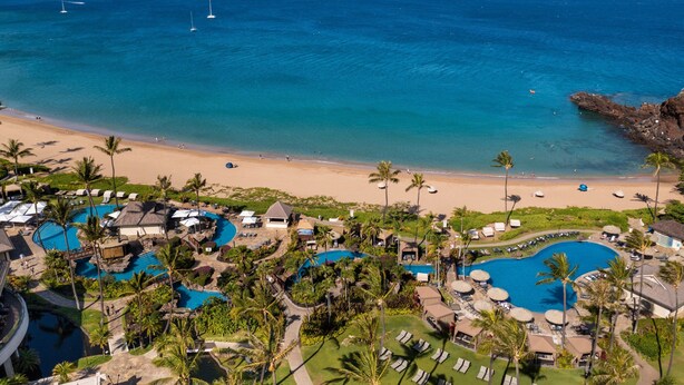 Resort com várias piscinas, uma praia e uma montanha ao fundo.
