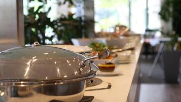 Buffet com pratos tampados e uma colher sobre um prato.