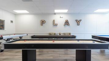 Uma mesa de bilhar com um aviso 'PLAY' acima, indicando uma área de lazer.