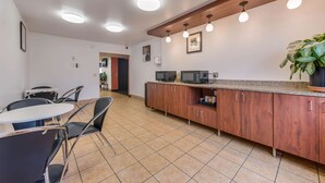 Cozinha moderna com bancada de madeira, micro-ondas embutido e um vaso com planta.