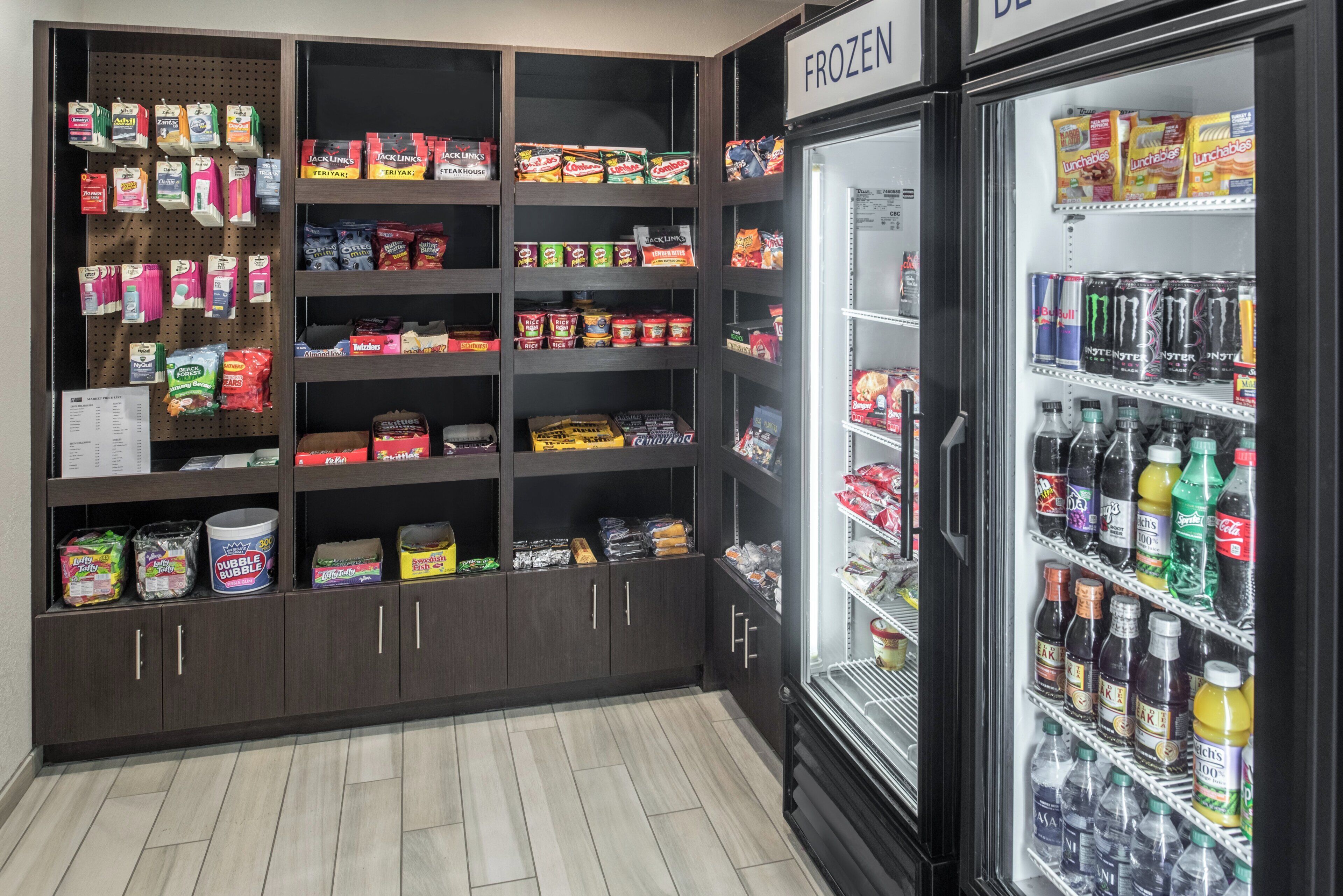 Exposição de lanches e bebidas numa loja, com diversos produtos embalados e uma área refrigerada.