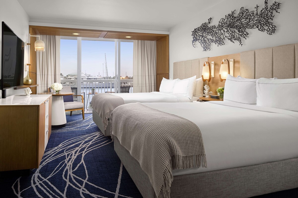 Quarto de hotel com uma cama grande, uma escrivaninha, uma cadeira e vista para a cidade.