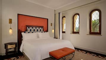 Quarto bem arrumado com cama grande, mesa de cabeceira, abajur e janela com vista.