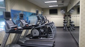 Academia com várias esteiras, bicicletas ergométricas e aparelhos de musculação.