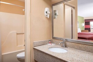 Casa de banho com lavatório, espelho e secador de cabelo fixado na parede.