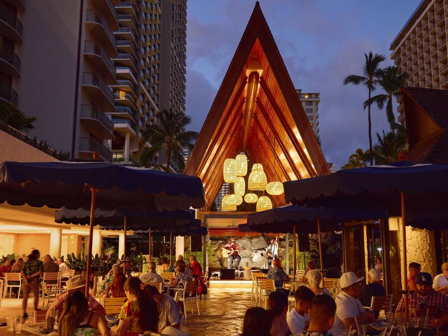 Um átrio de hotel com palco para apresentações, assentos ao ar livre e vista dos edifícios ao redor.