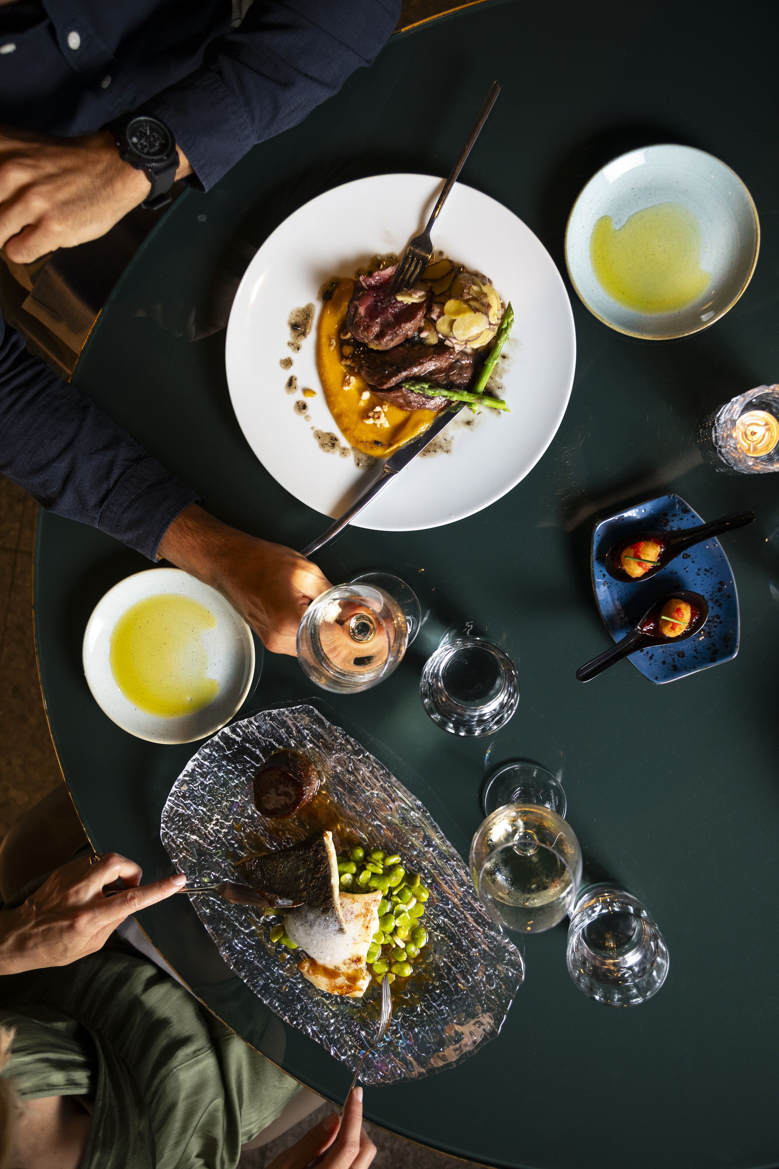 Uma mesa de jantar com pratos de comida, copos e talheres.
