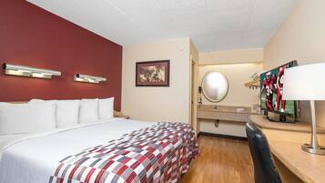 Quarto de hotel com cama, escrivaninha com espelho e televisão.