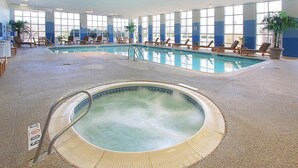 Piscina interna com banheira de hidromassagem, espreguiçadeiras e janelas amplas.